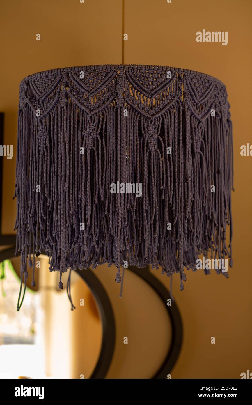 Macrame lampshade with fringes, suspended in front of a warm ...