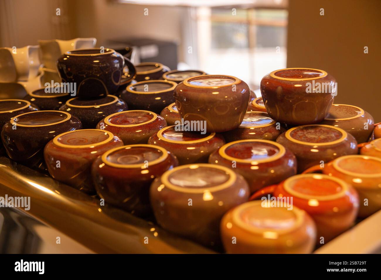 Handmade ceramic mugs drying on a coffee machine lid in a cozy coffee ...