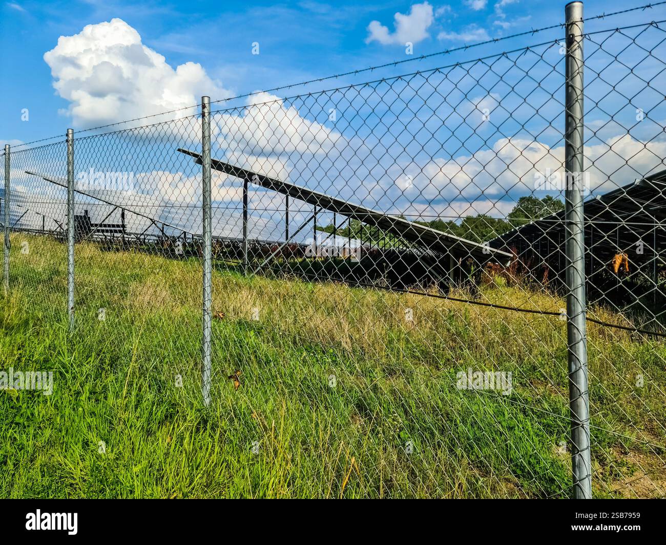 Chain link fence protecting solar panels in a field, renewable energy ...