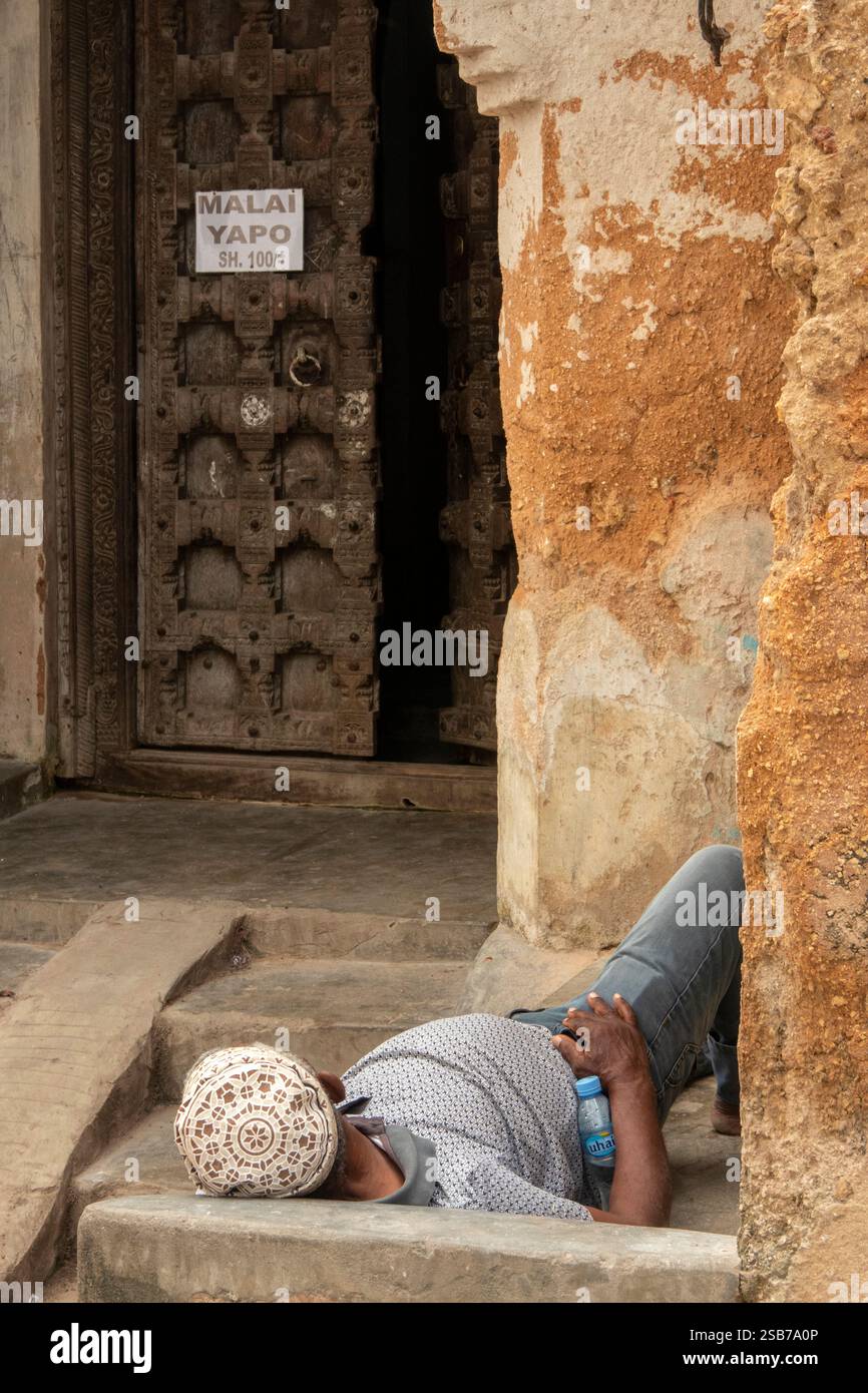 Africa Tanzania, Zanzibar, Stonetown, old town, Mkunazini, man asleep in doorway on baraza ...