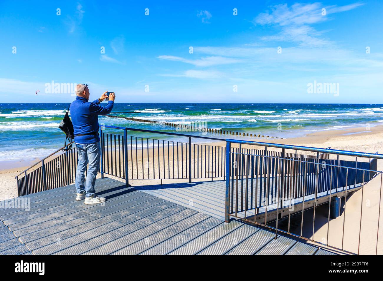 Unidentified man taking photo of beautiful beach and sea from lookout ...