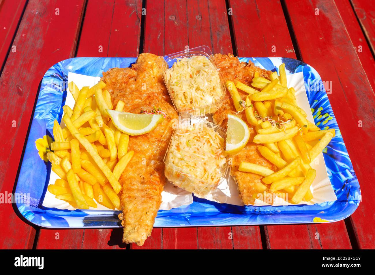 Fried cod fish with french fries and salad on wooden table in costal ...
