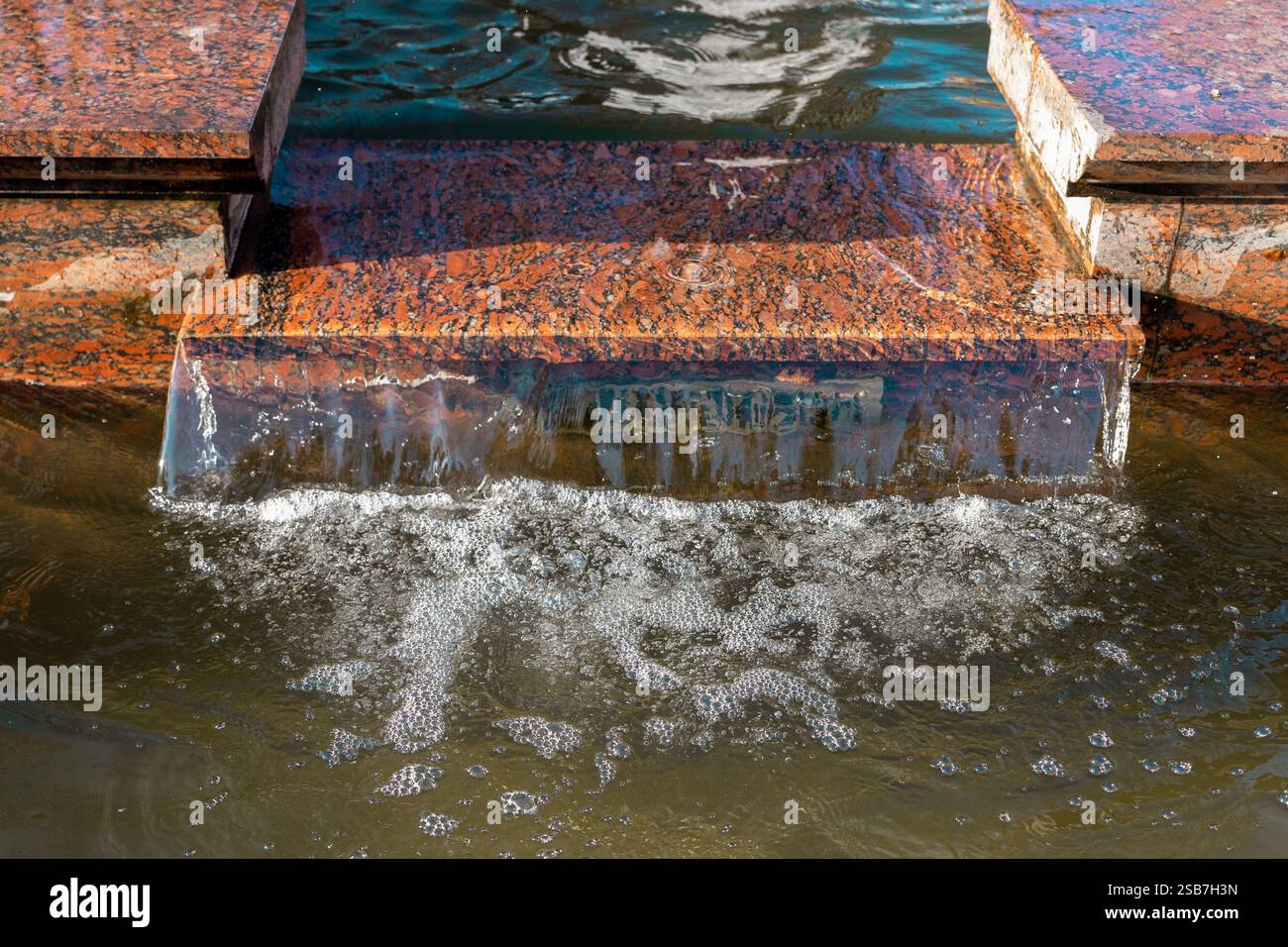 Water flows gently over a smooth granite ledge, creating bubbles and ...