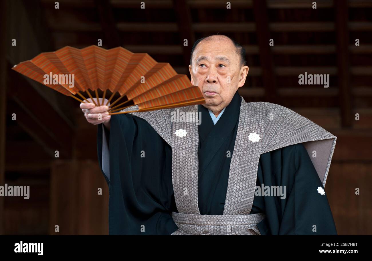 Performer in traditional Noh costume holding fan executes a move on ...