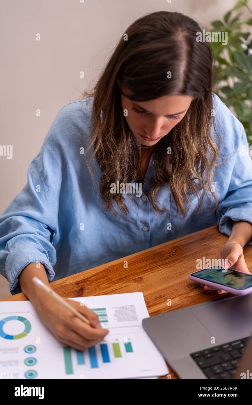 Young professional woman multitasking at work, using smartphone while ...