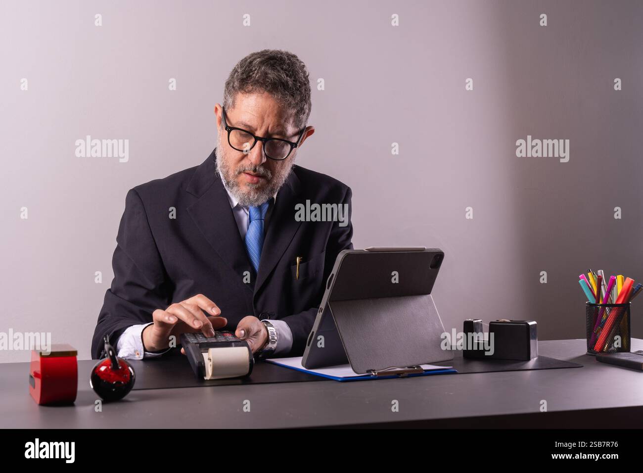 Business executive using a calculator at an office desk, focusing on ...