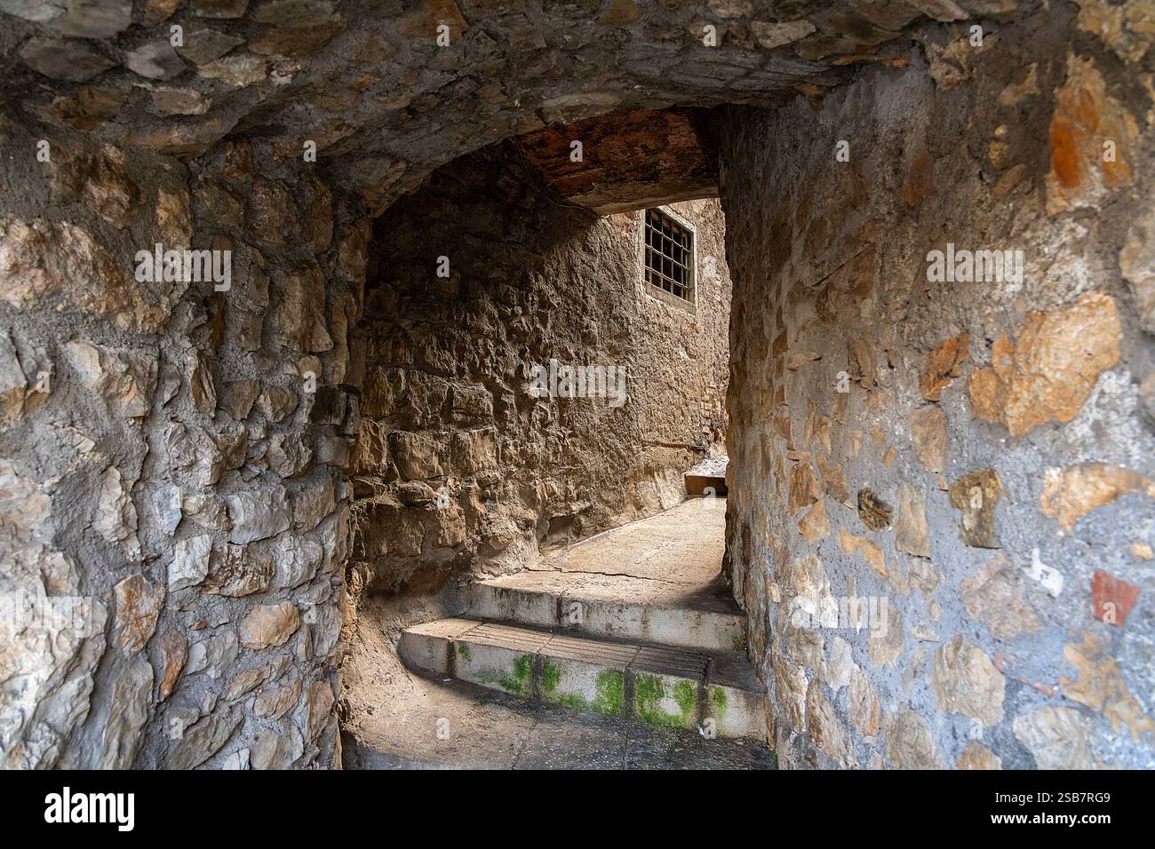 ancient medieval passage with stone vault and a small window closed by ...