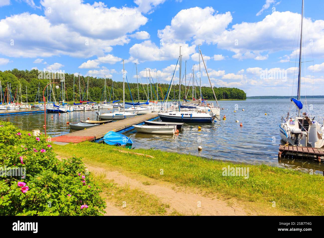 Sailing boats and pier on lake shore in Karwica village port on sunny ...