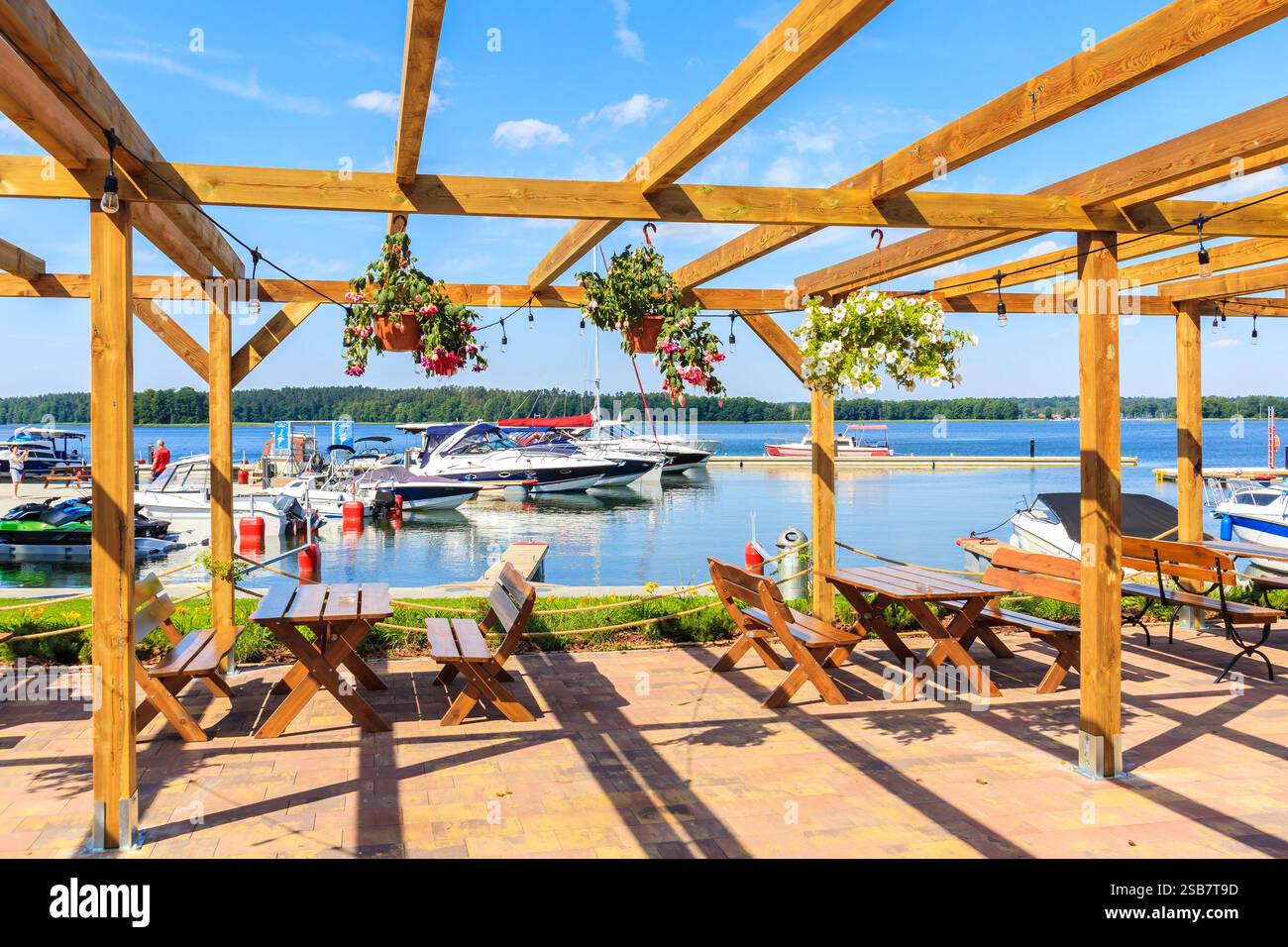 Restaurant tables on terrace with flowers and view of sailing boats on ...