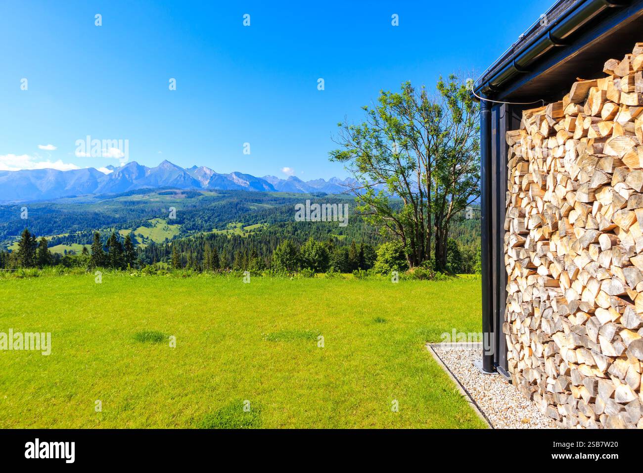 Wood stack near house at Lapszanka Pass and view of Tatra Mountains ...