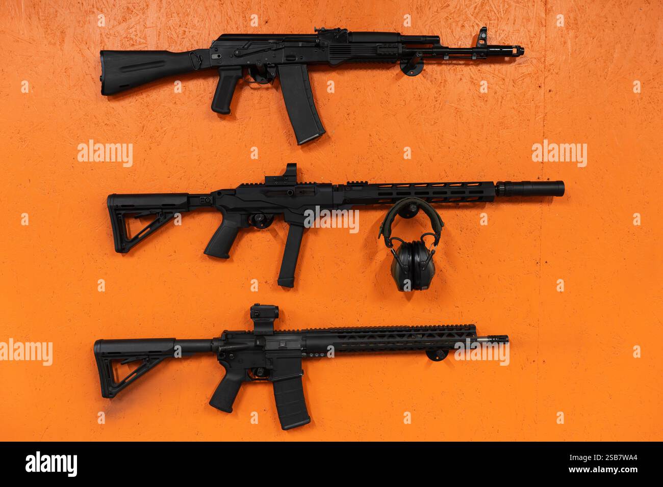 Modern small arms in a shooting range on an orange wall. Rifles and ...