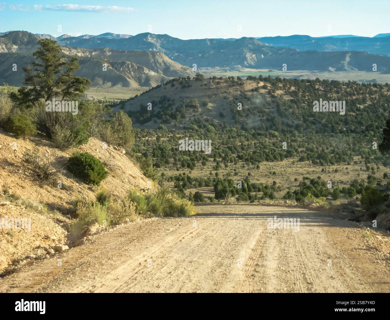 A dirt road winds through a desert landscape. The road is rocky and ...