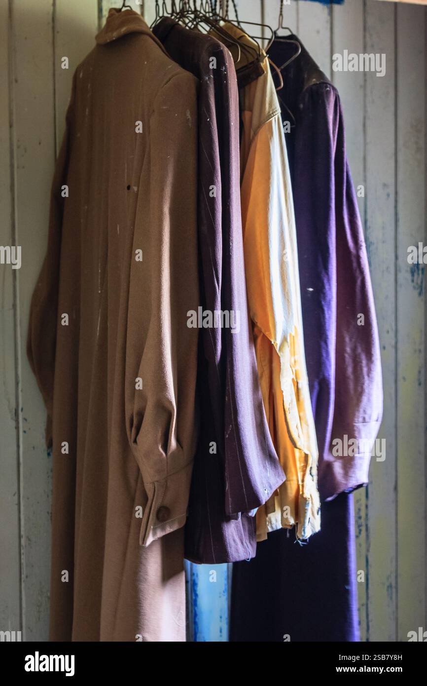 Three long coats hanging on a rack, one of which is brown and the other ...