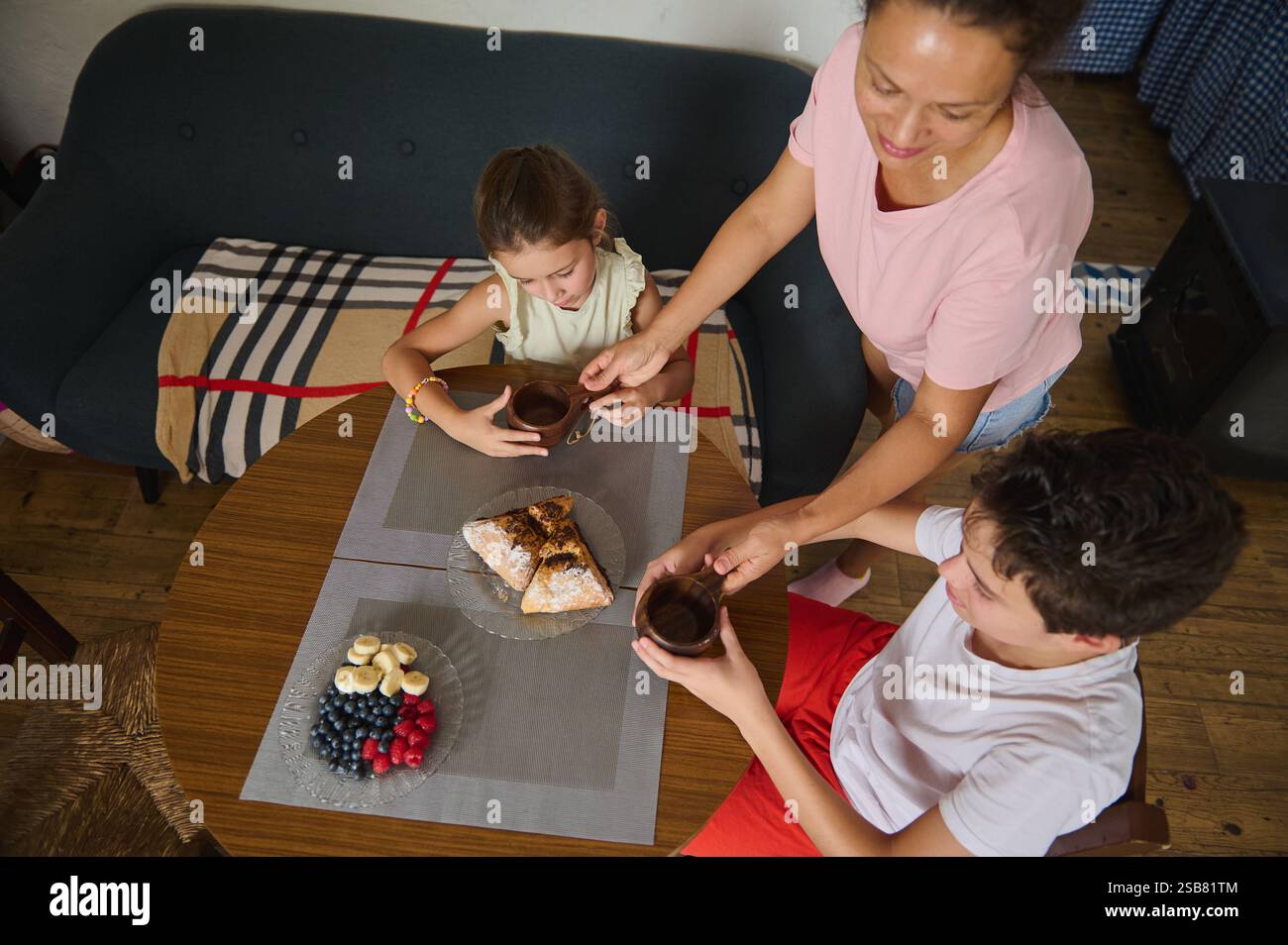 A family gathering around a wooden table, sharing breakfast with ...