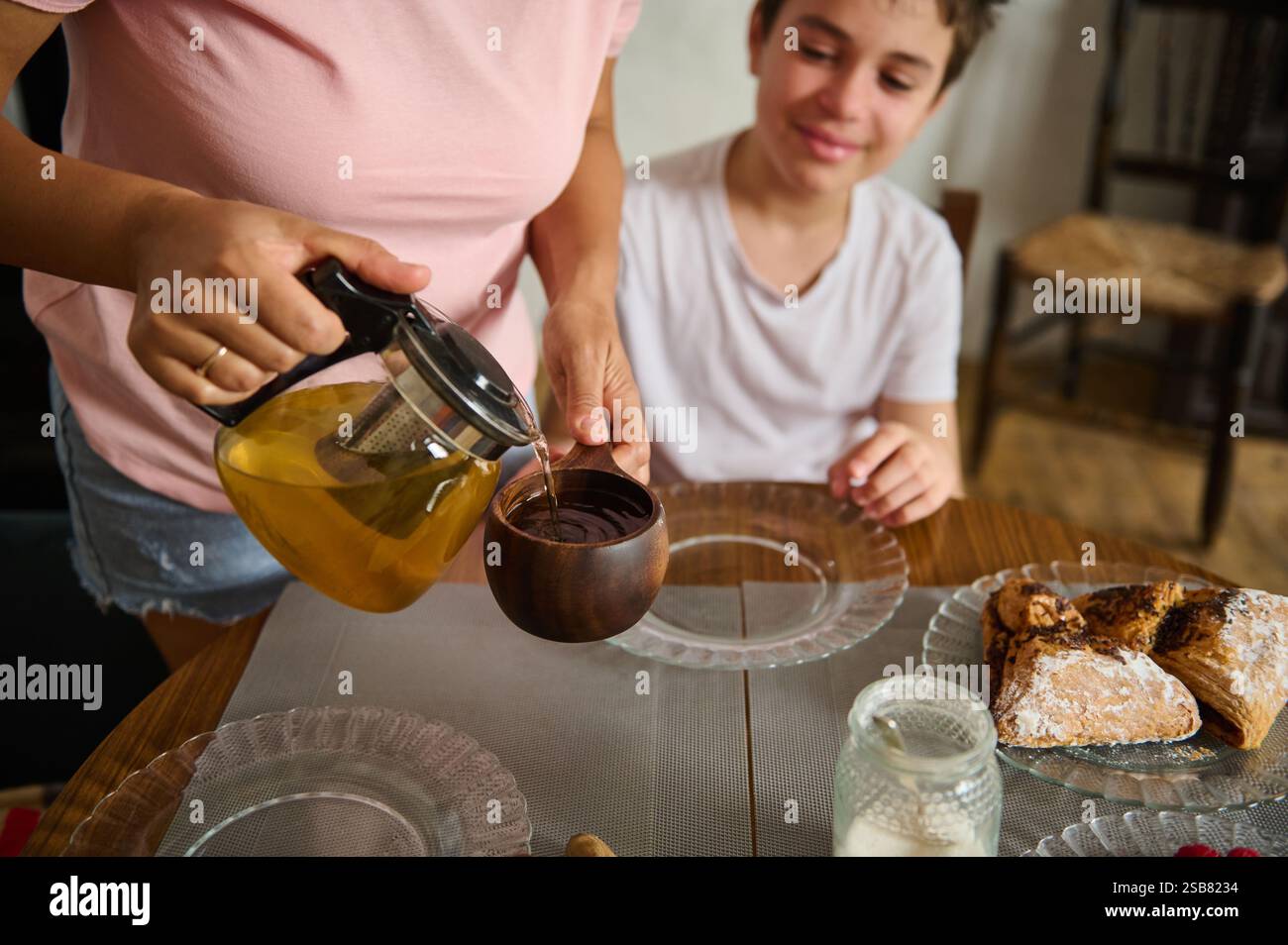 A warm scene showing a parent pouring fresh tea while a child enjoys ...