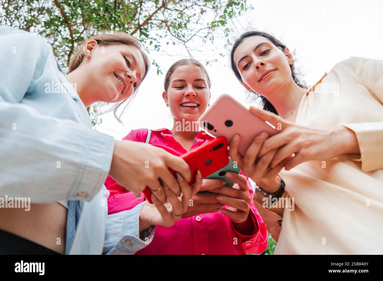 Three Young Women Engaged in a Lively Interaction While Using Their ...