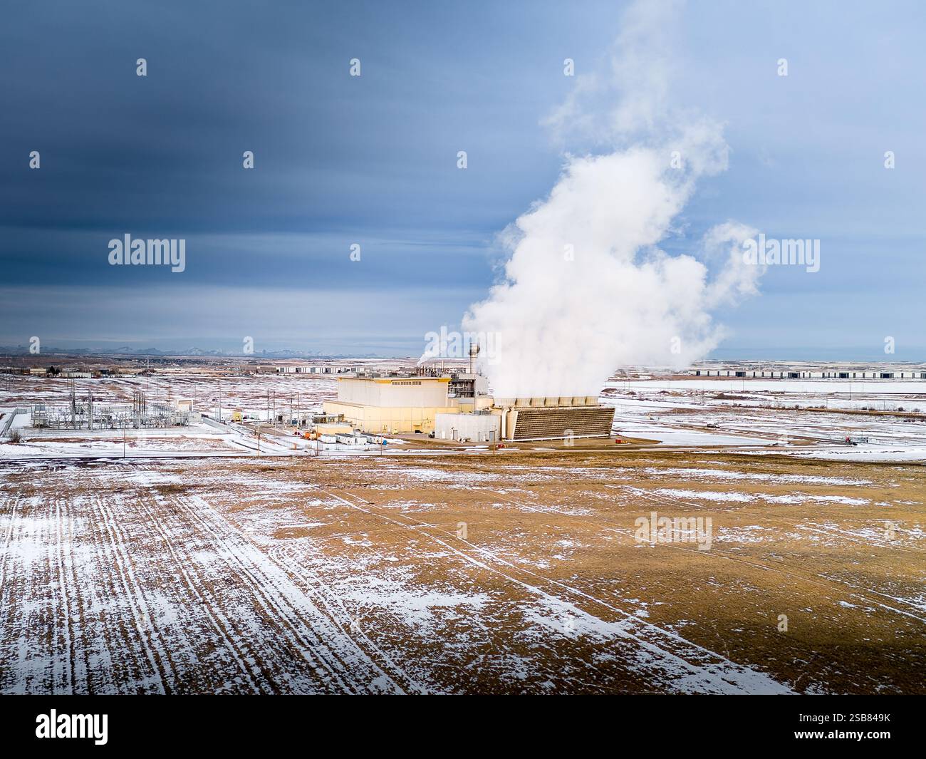 Power plant under winter sky producing electricity with steam rising ...