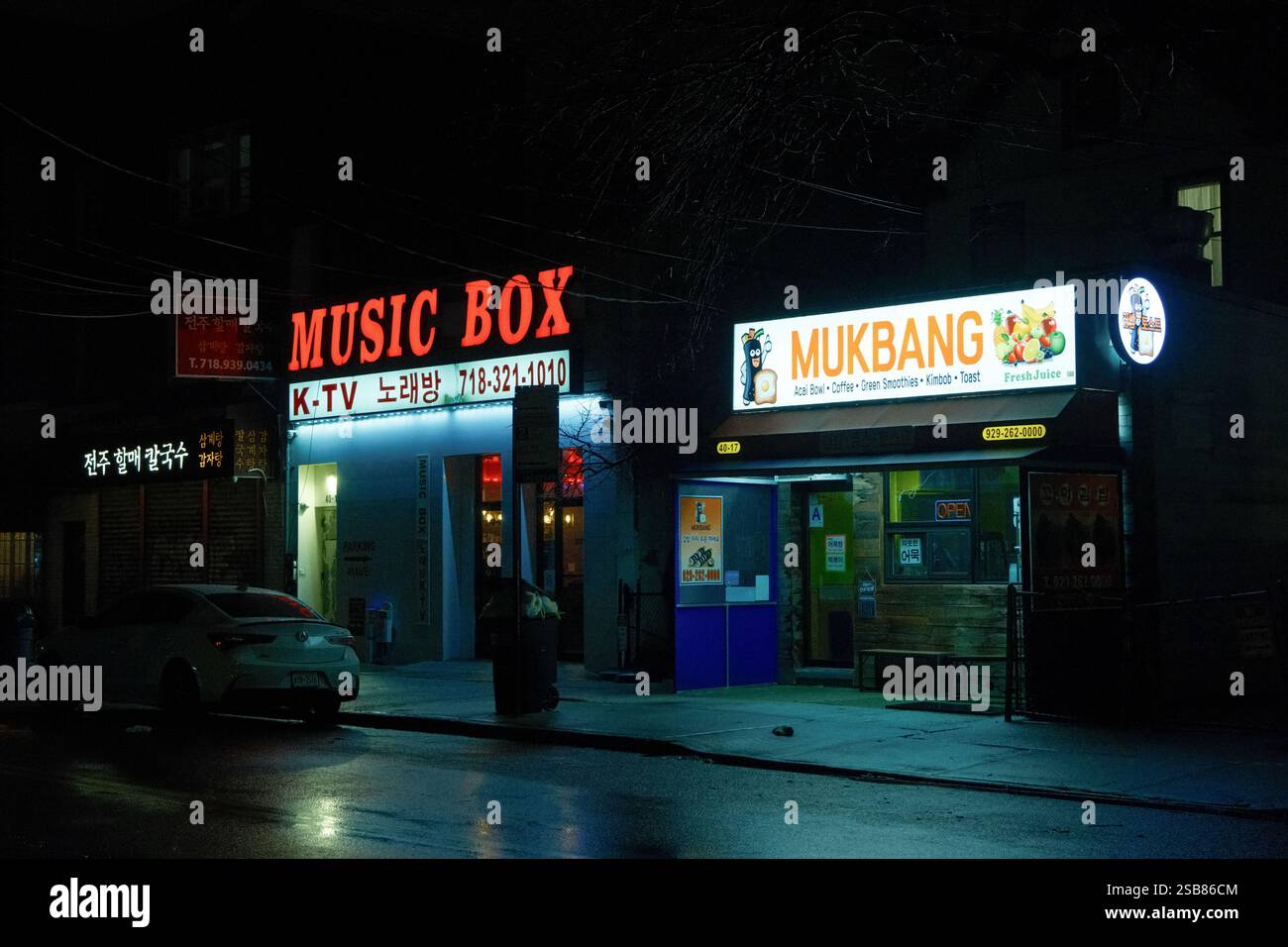 Storefronts with neon signs for a karaoke bar and a cafe at night in ...