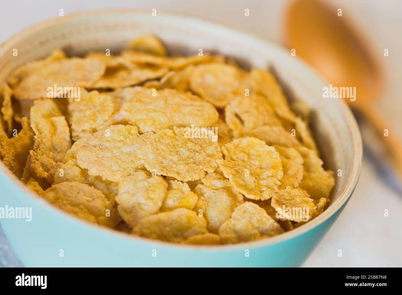 Crispy unsweetened corn flakes in blue bowl, photographed with natural ...