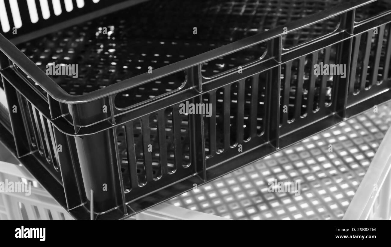 A black plastic container with a mesh design sits on a white surface ...