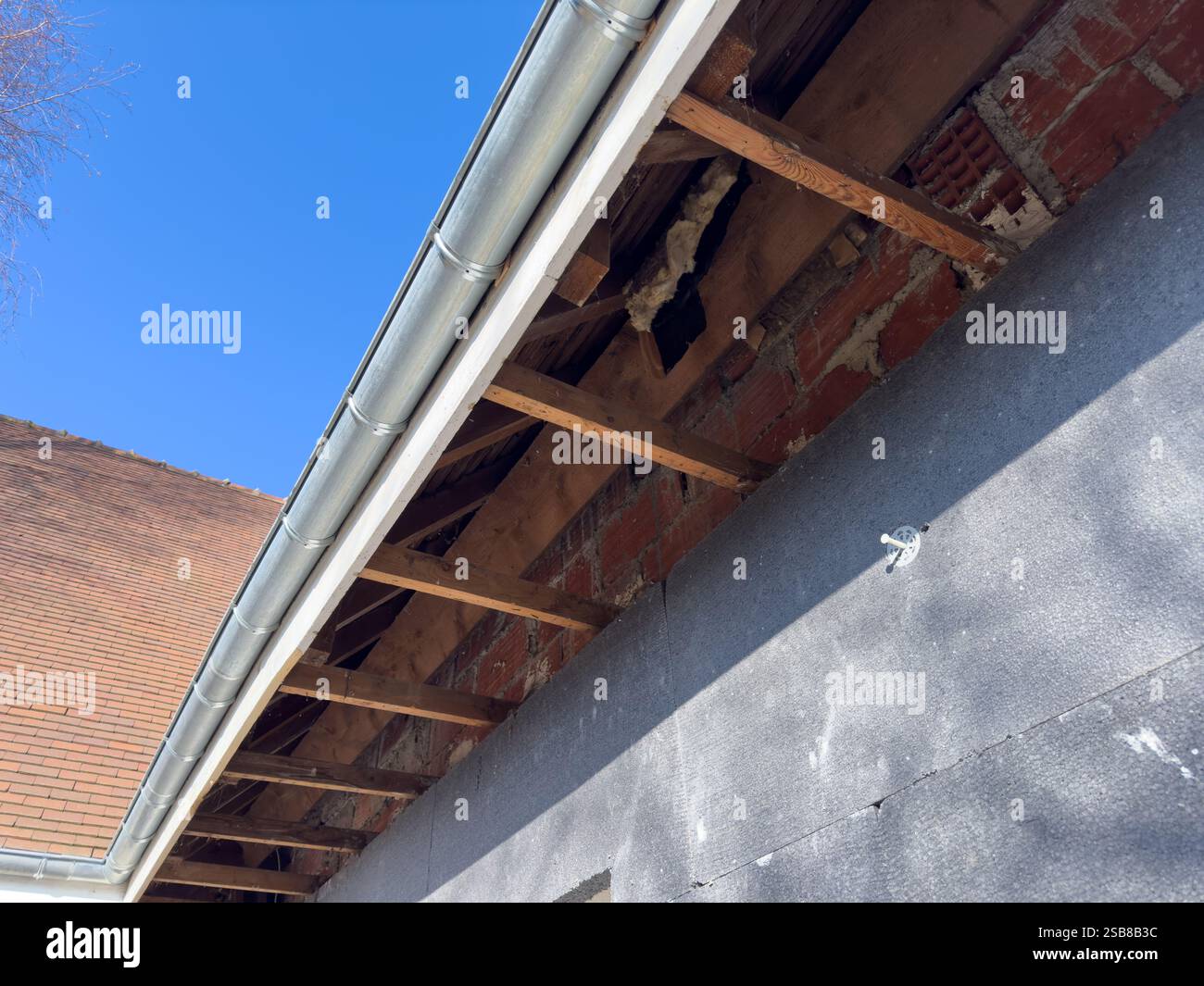Home renovation reveals open roof structure under a clear blue sky ...