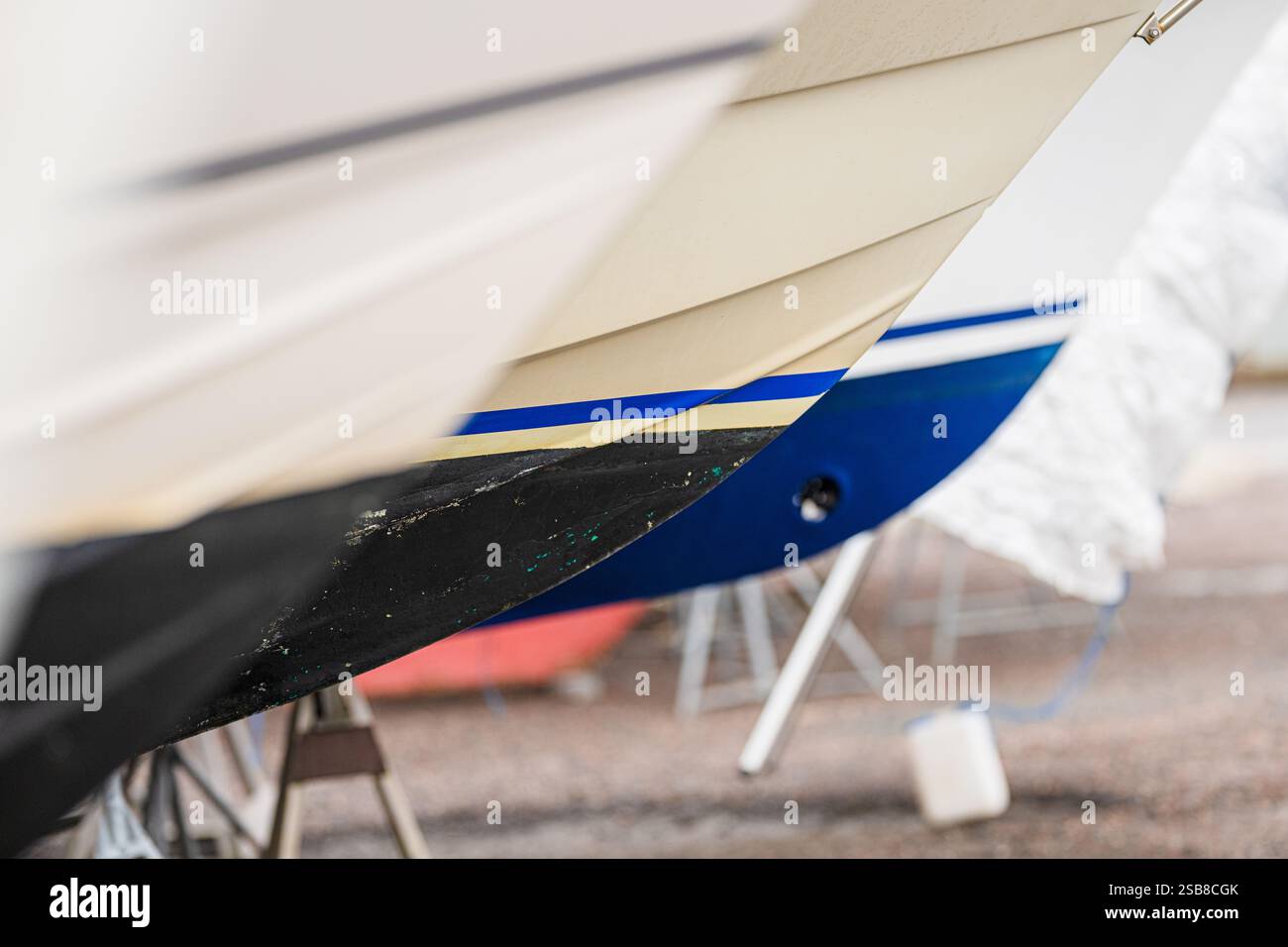 hulls of boats on stands in boatyard showing various paint schemes ...