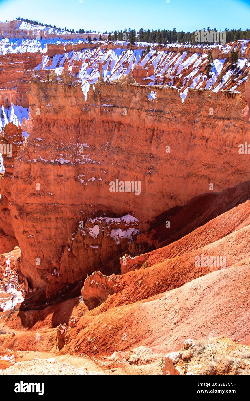 A rocky cliff with snow on it. The snow is melting and the ground is ...