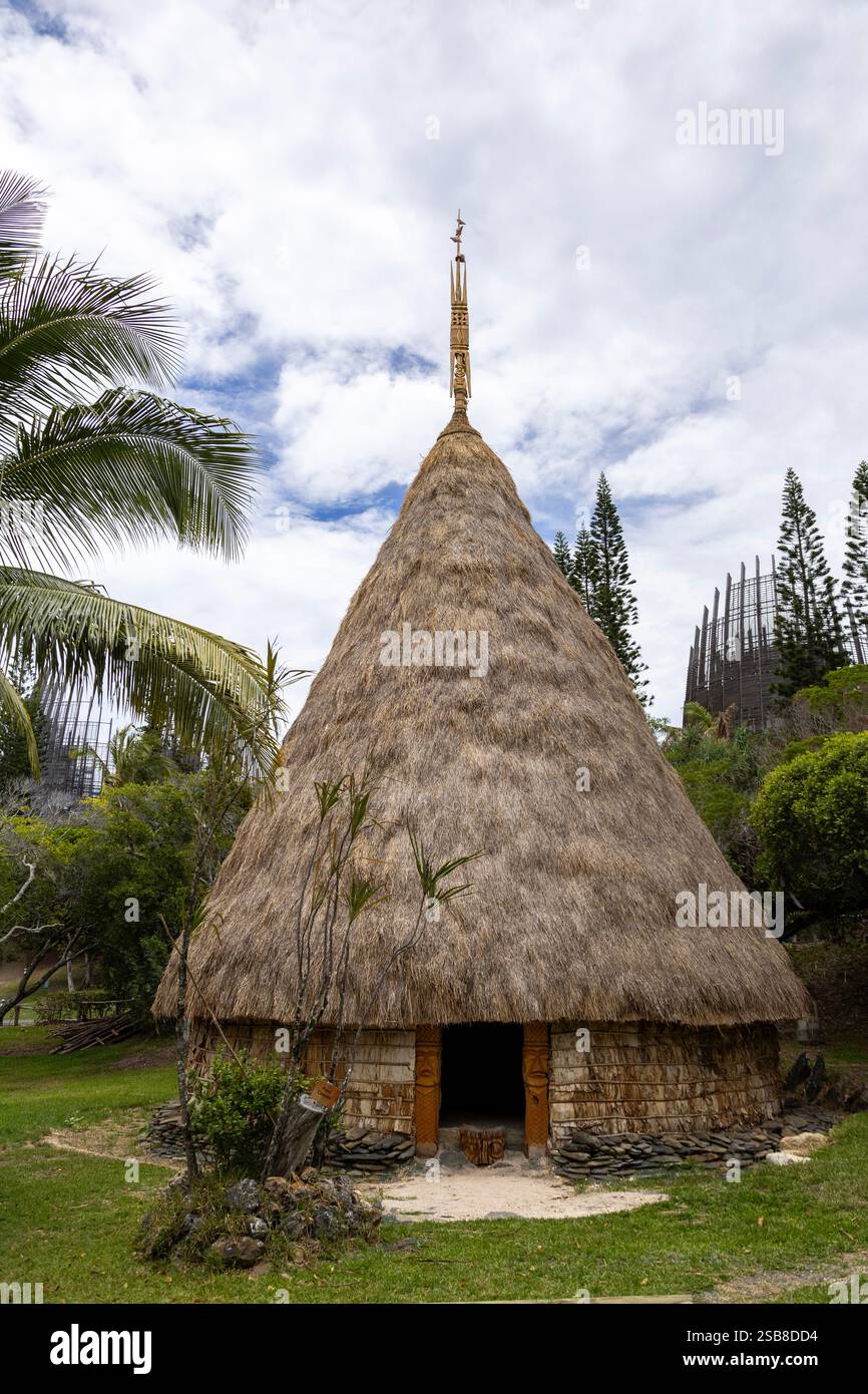 Traditional chiefs hut with a thatched roof and a carved rooftop spear in the Tinu Peninsula ...