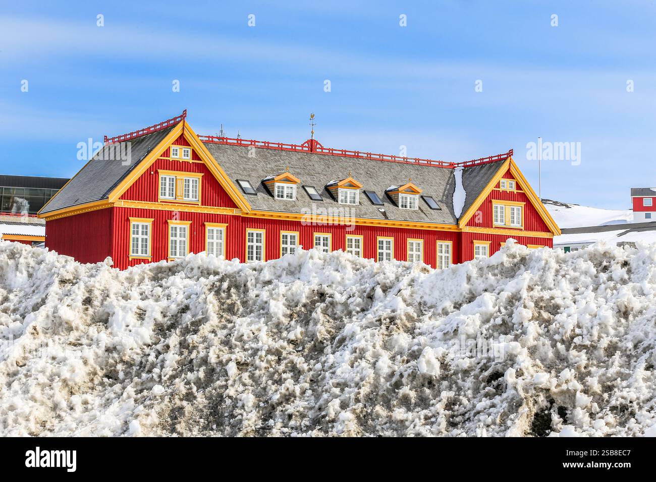 Old red Danish colonial building with snow heap in the foreground ...
