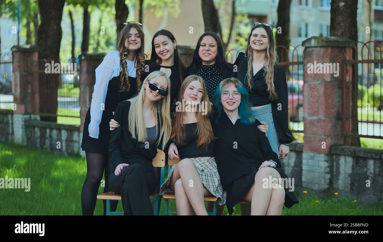Happy students gathering on a bench in the schoolyard, enjoying their ...