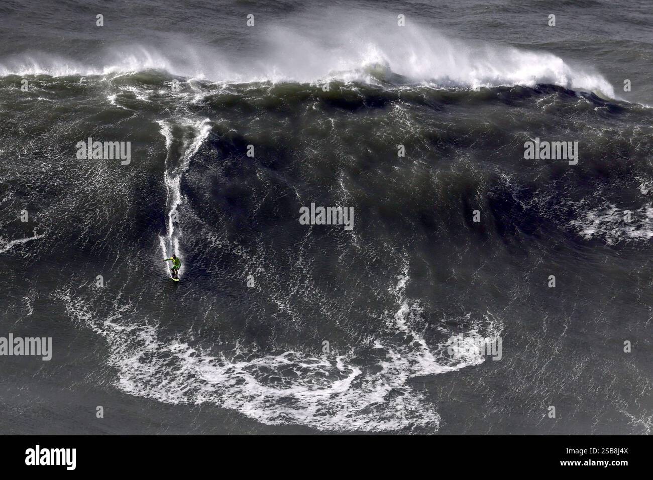 NAZARE, PORTUGAL - JANUARY 28: Surfer riding a big wave during a ...