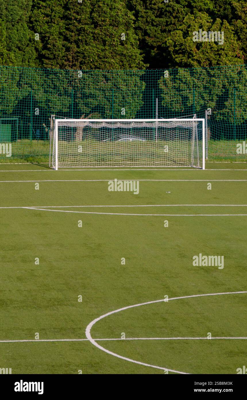 A soccer goal stands empty on a neatly trimmed field, with lush ...