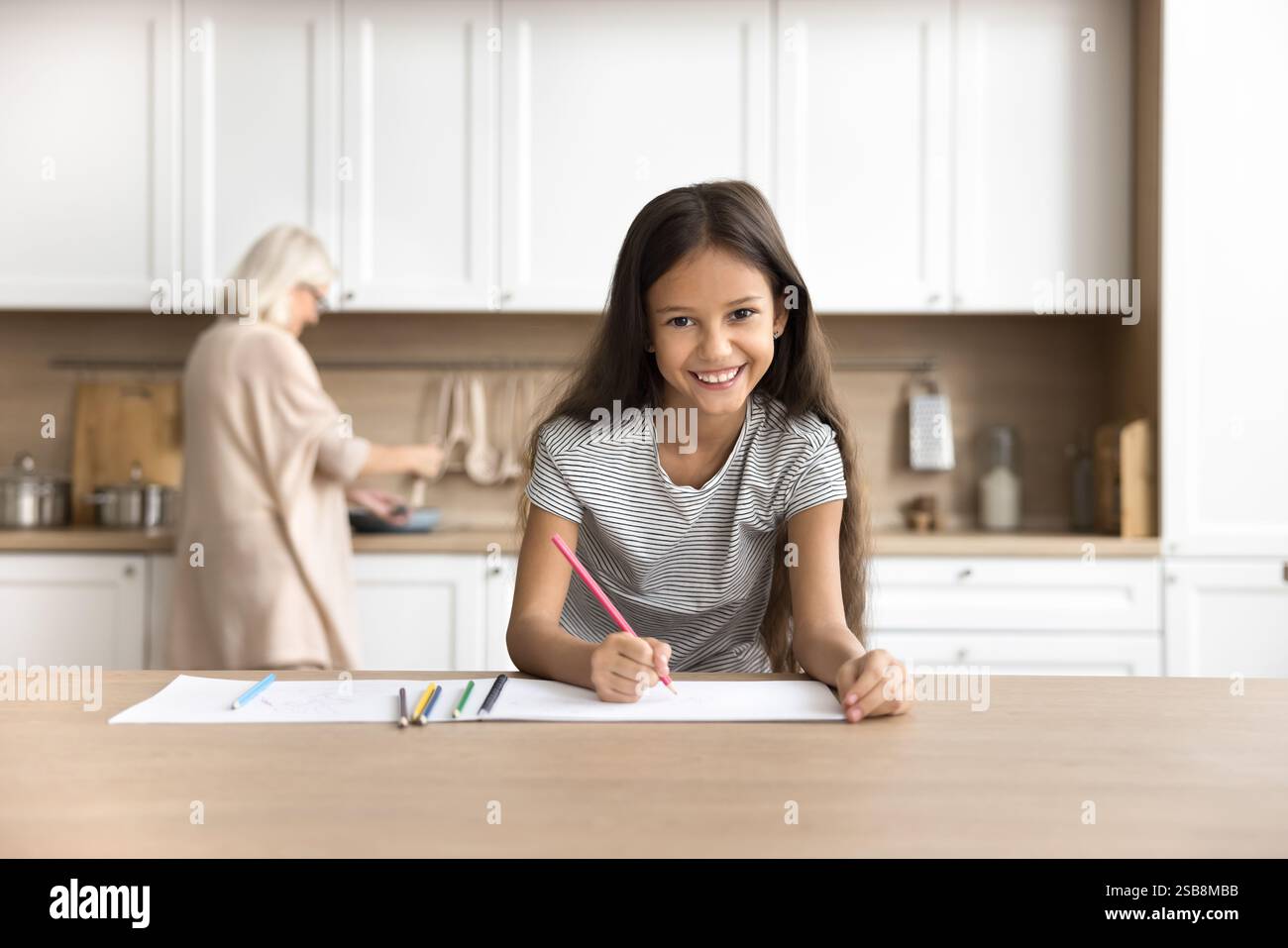 Smiling tween girl drawing while aged grandma cooking at kitchen Stock Photo - Alamy