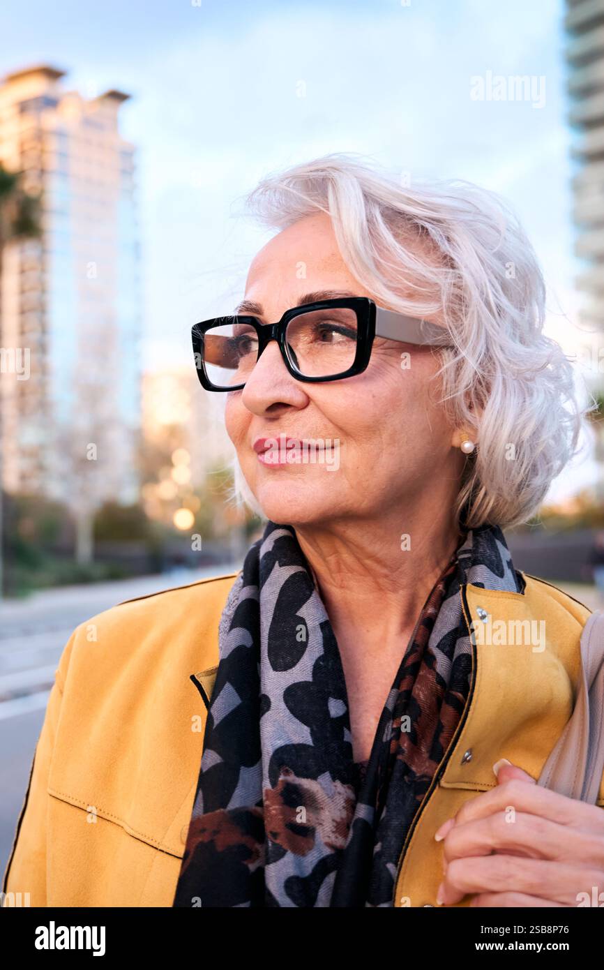 Elegant senior woman walking in the city at dusk, enjoying retirement ...