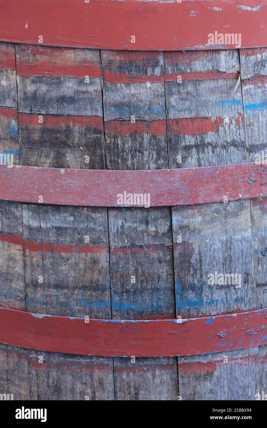 A wooden barrel with red and blue stripes. The barrel is old and has a ...