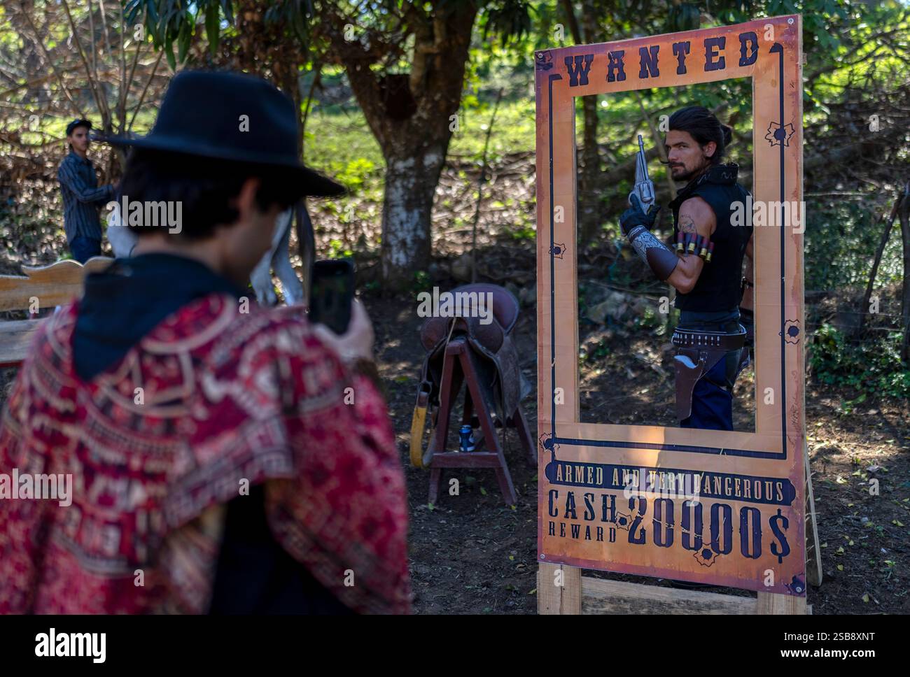 A cosplayer poses for a photo framed by a wanted poster stand during a ...