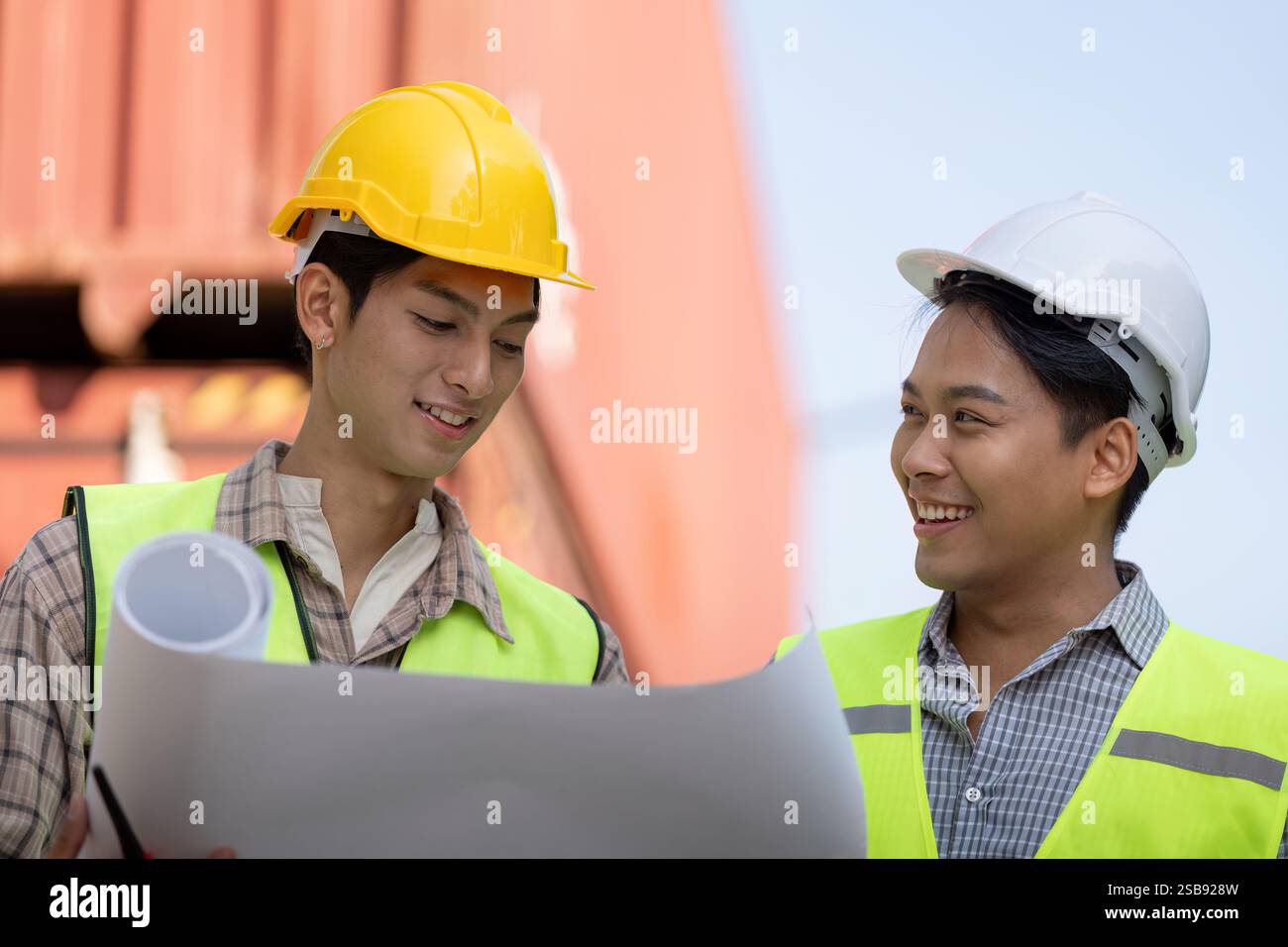Logistics engineer and colleague smiling while reviewing construction ...