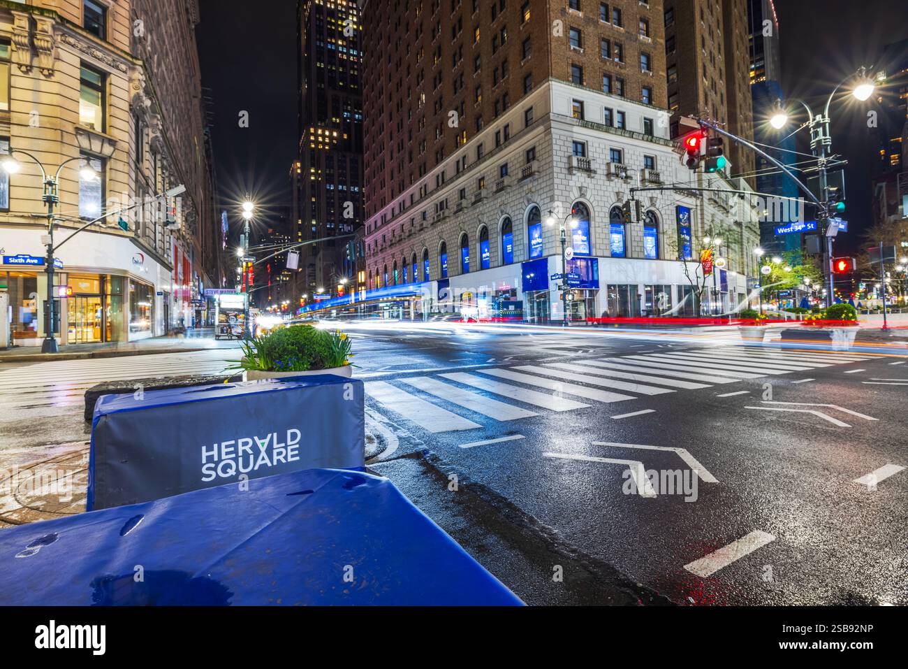Herald Square at night with wet pavement, crosswalk, traffic light and ...