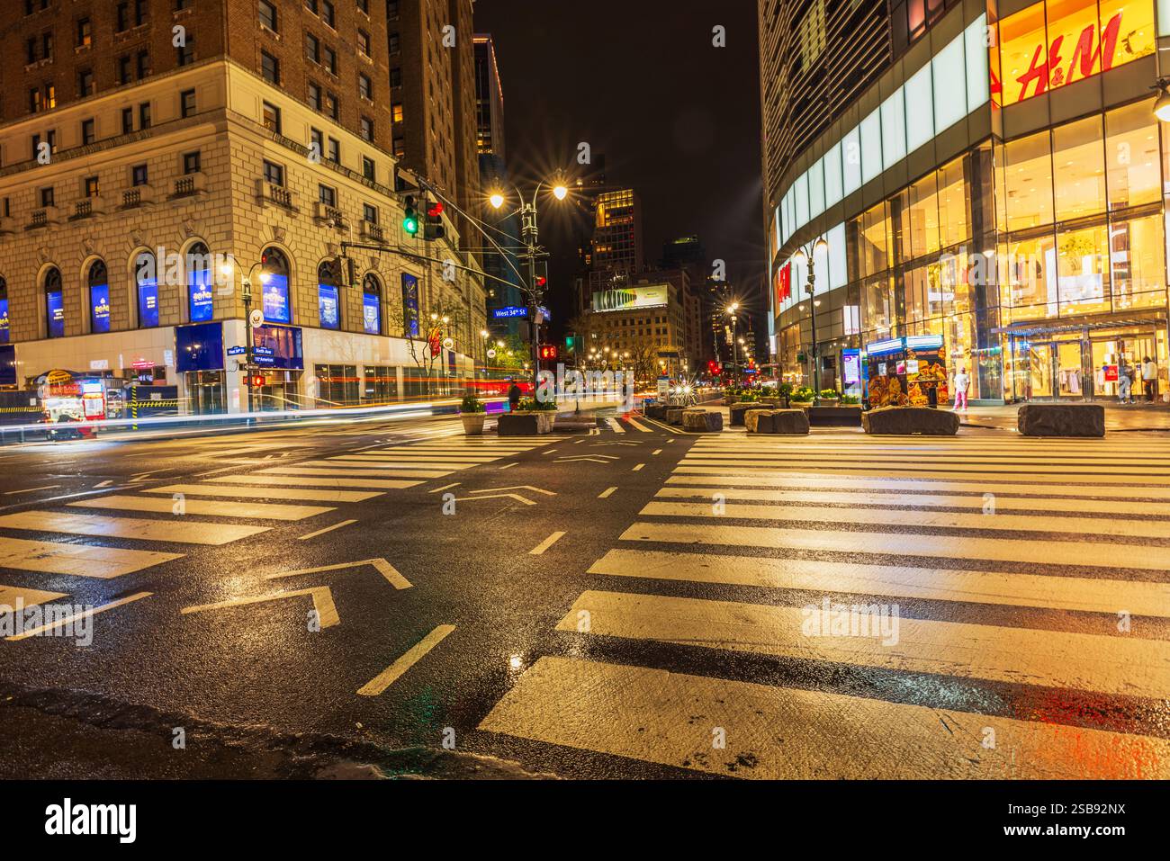 Wet pedestrian crosswalk at night with motion blur of passing vehicles ...