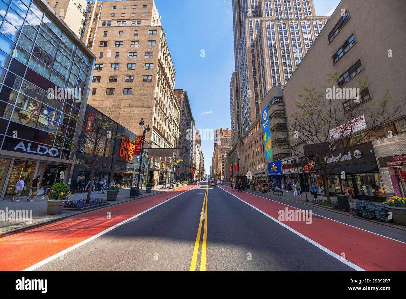 Wide street in New York City with red bus lanes, storefronts and ...