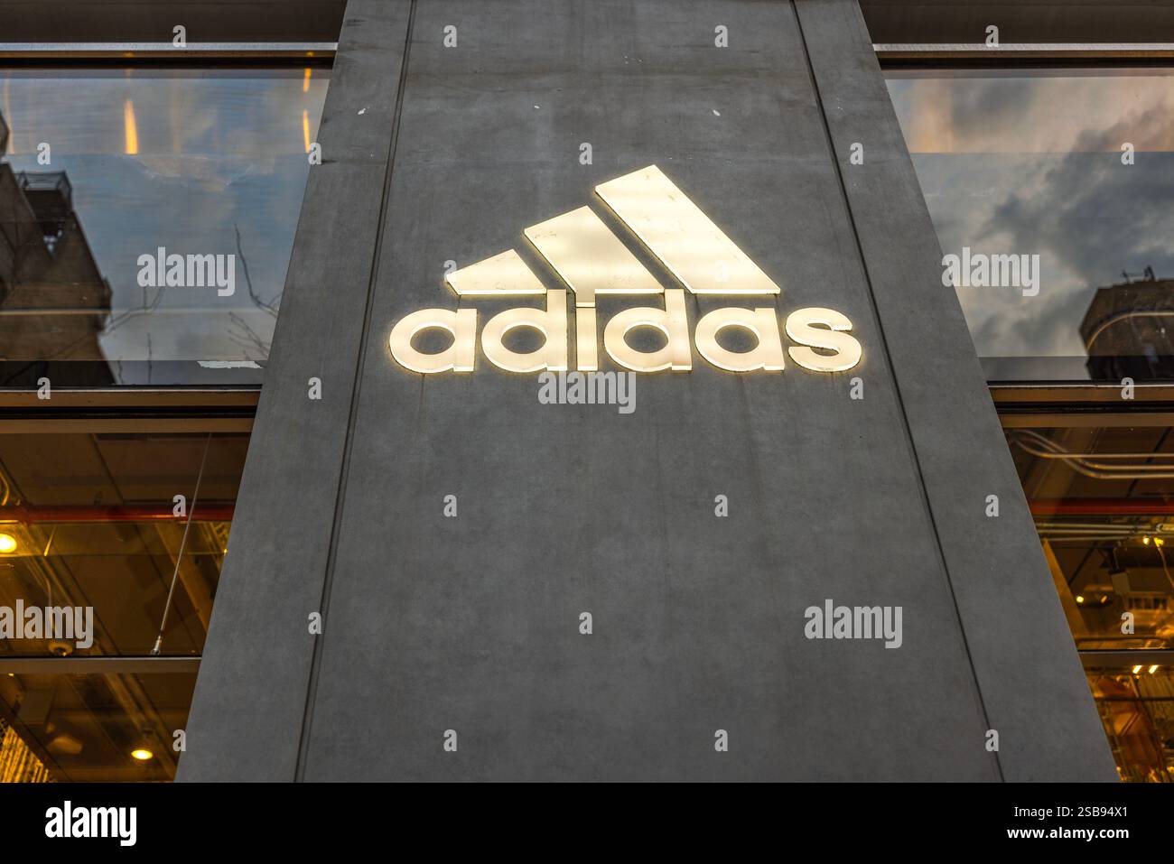 Close-up view of illuminated Adidas logo on modern concrete storefront ...