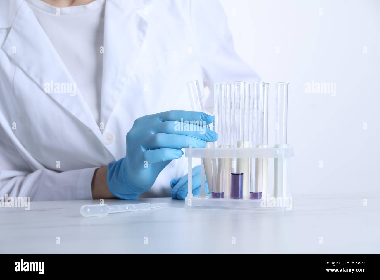 Laboratory testing. Scientist working with test tubes at white marble ...