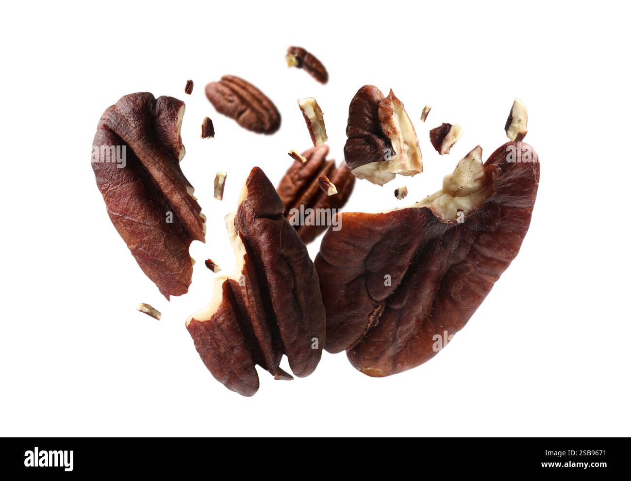 Broken pecan nuts in air on white background Stock Photo - Alamy