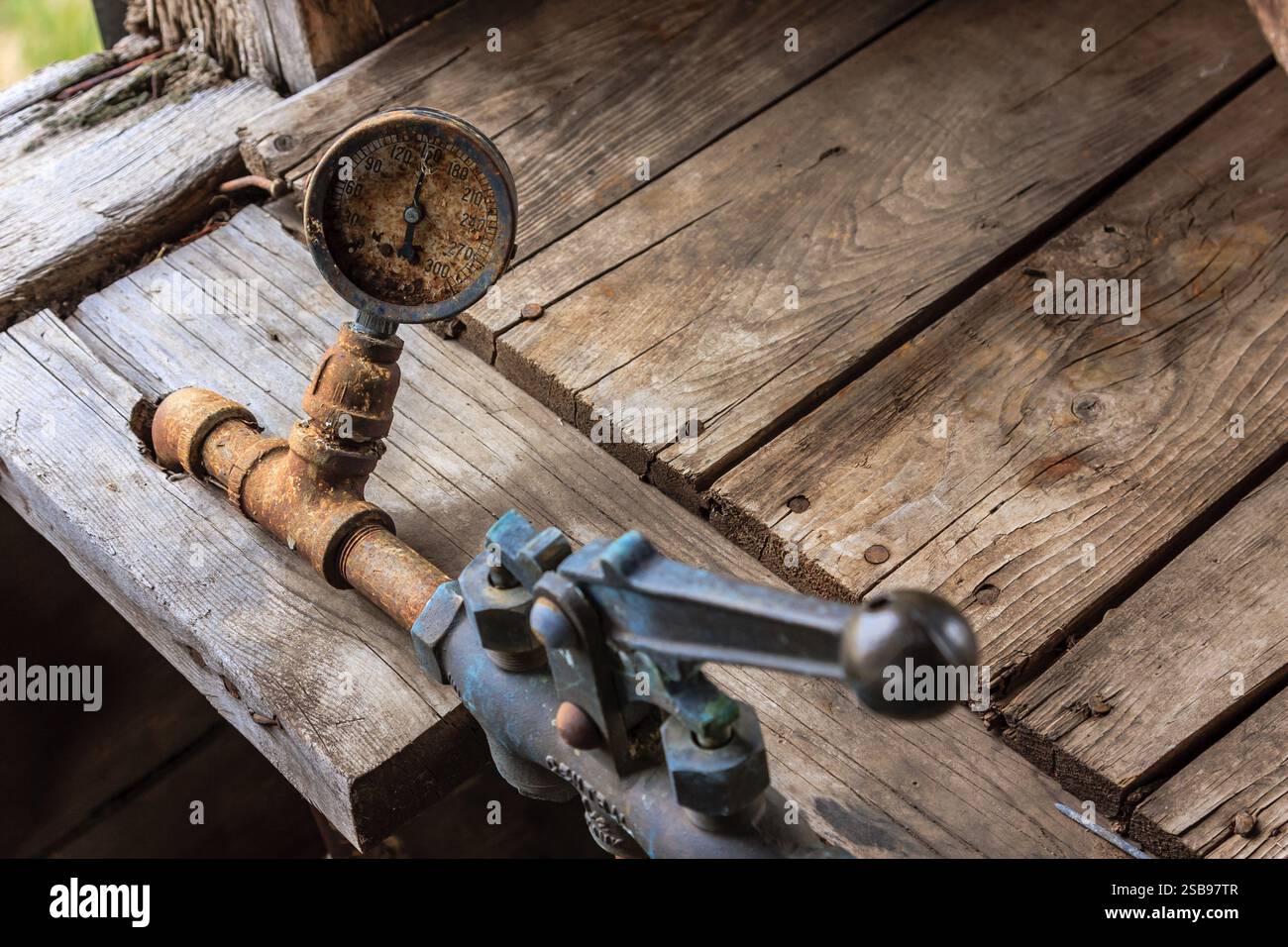 A rusty old pipe with a blue valve on top of it. The valve is open and ...