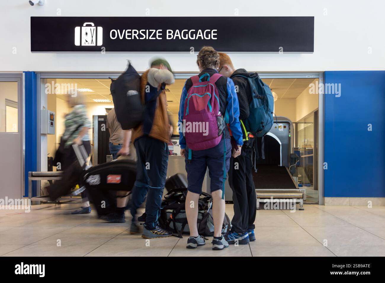 Passengers with luggage queue in front of the airport's oversized ...