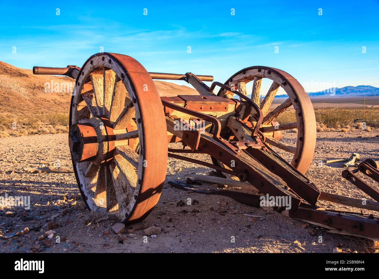 An old, rusted wheelbarrow sits in the desert. The scene is desolate ...