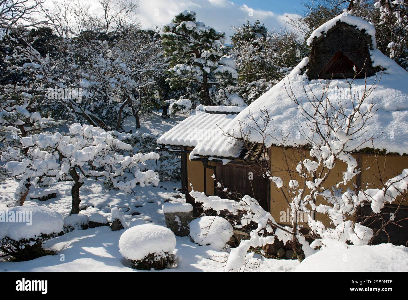 Lovely winter calendar scene of a thatched-roof hut covered in snow at ...