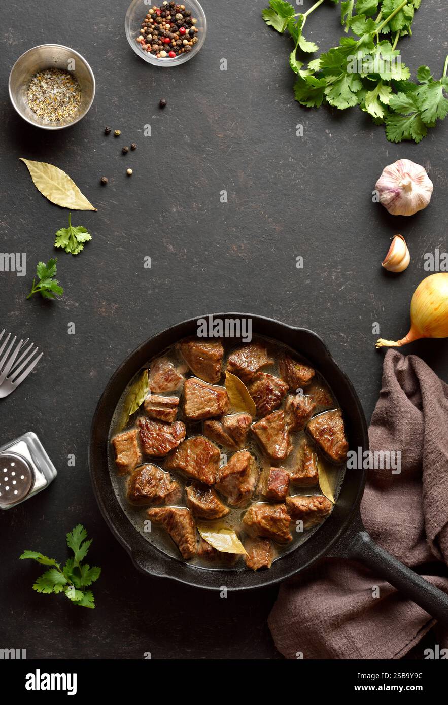 Stewed beef in cast iron skillet over dark stone background. Beef ...