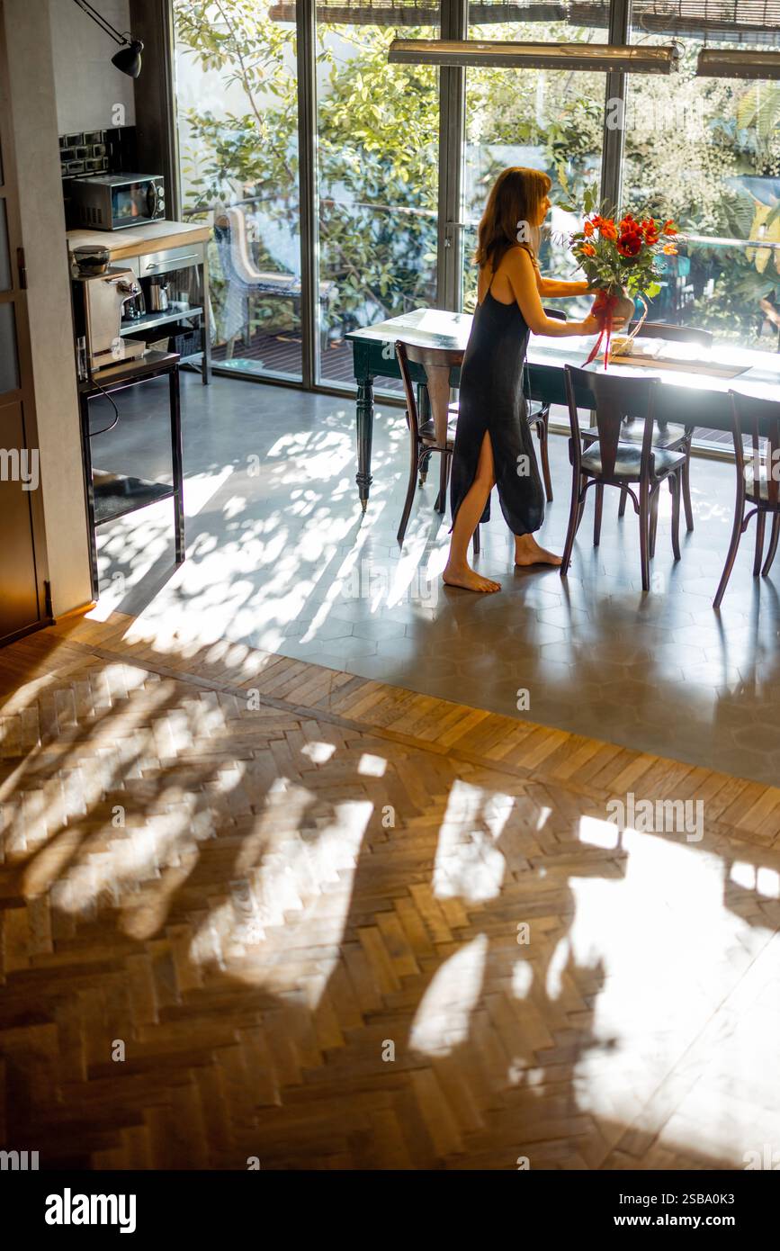 A barefoot woman in a minimalist dress walks through a bright, open ...