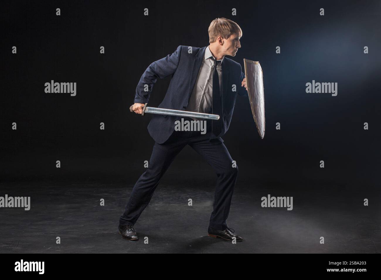 In a dramatic studio pose, a man in a navy suit stands poised with a ...